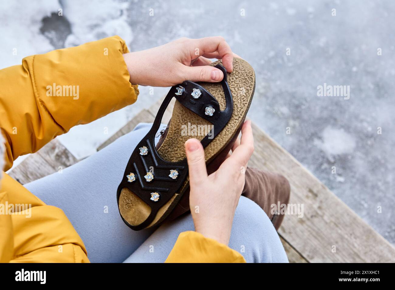 Rubber lining with spikes is stretched onto sole of winter boot to ...