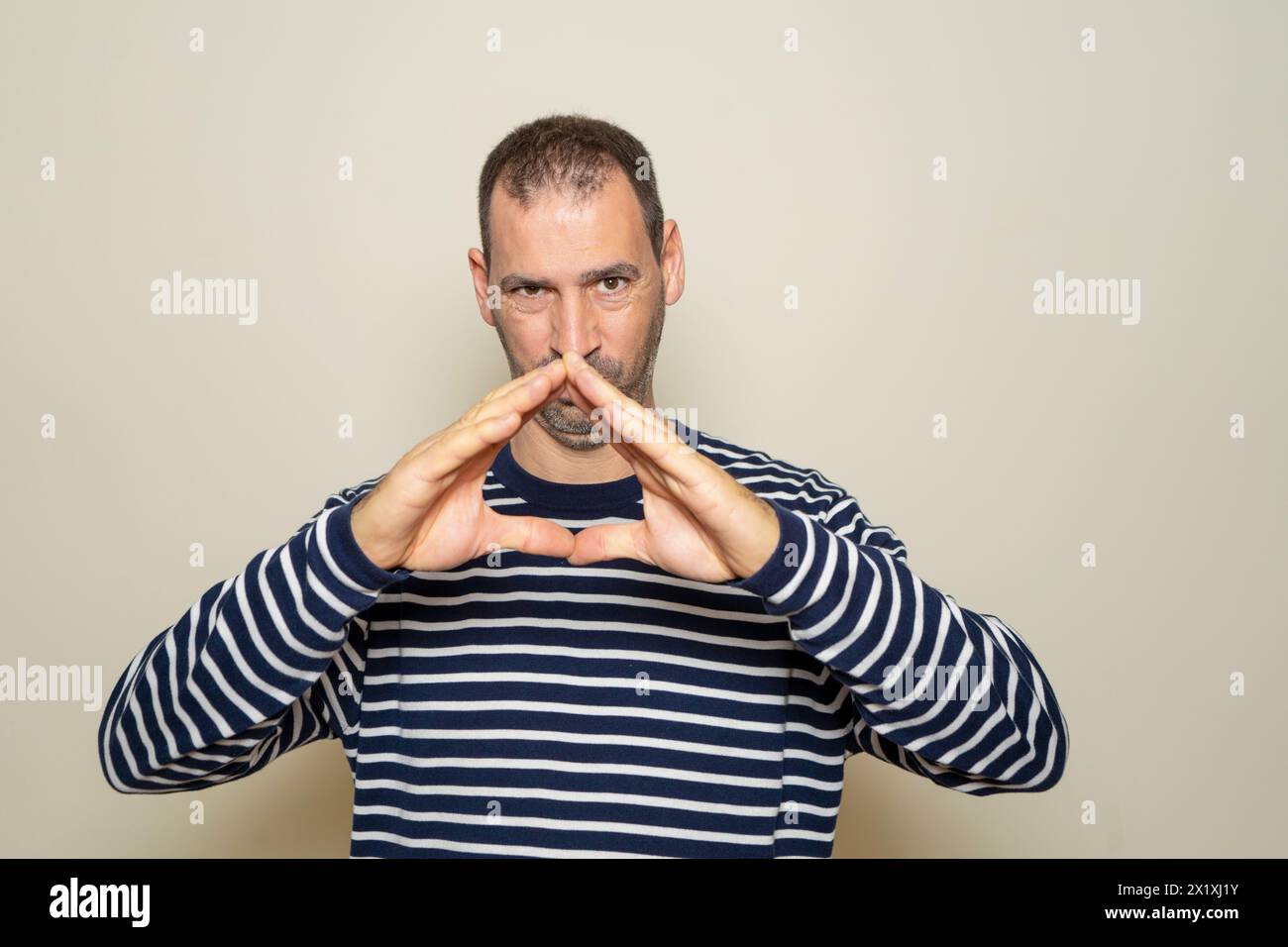 Hispanic man with a beard with his fingertips together in an expression ...