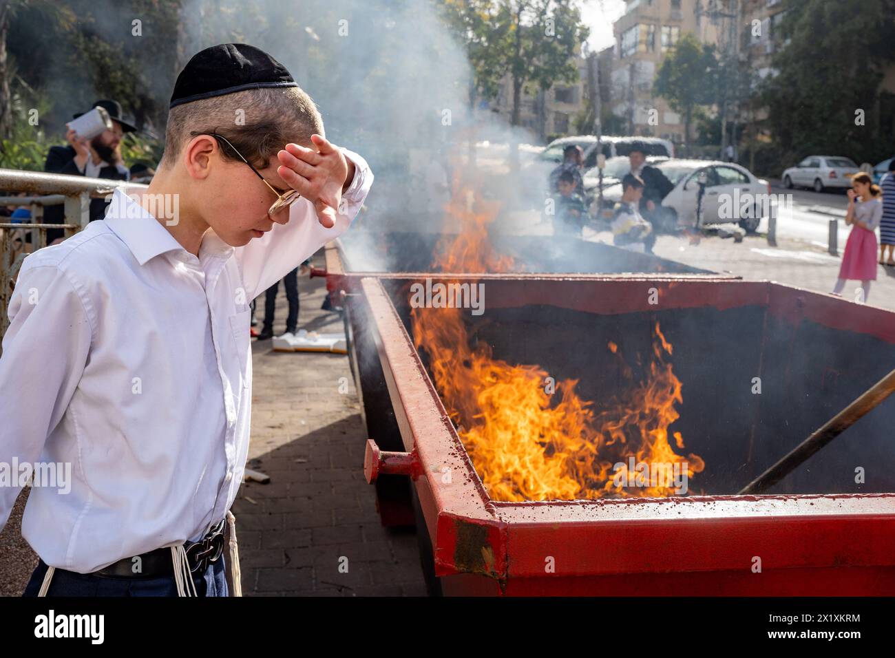 A Jewish boy stands next to the fire for burning the leaven before the ...