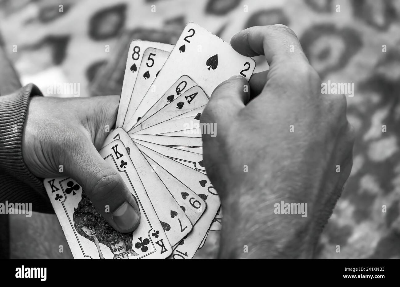 Black and white dramatic close-up of hands holding a variety of playing ...
