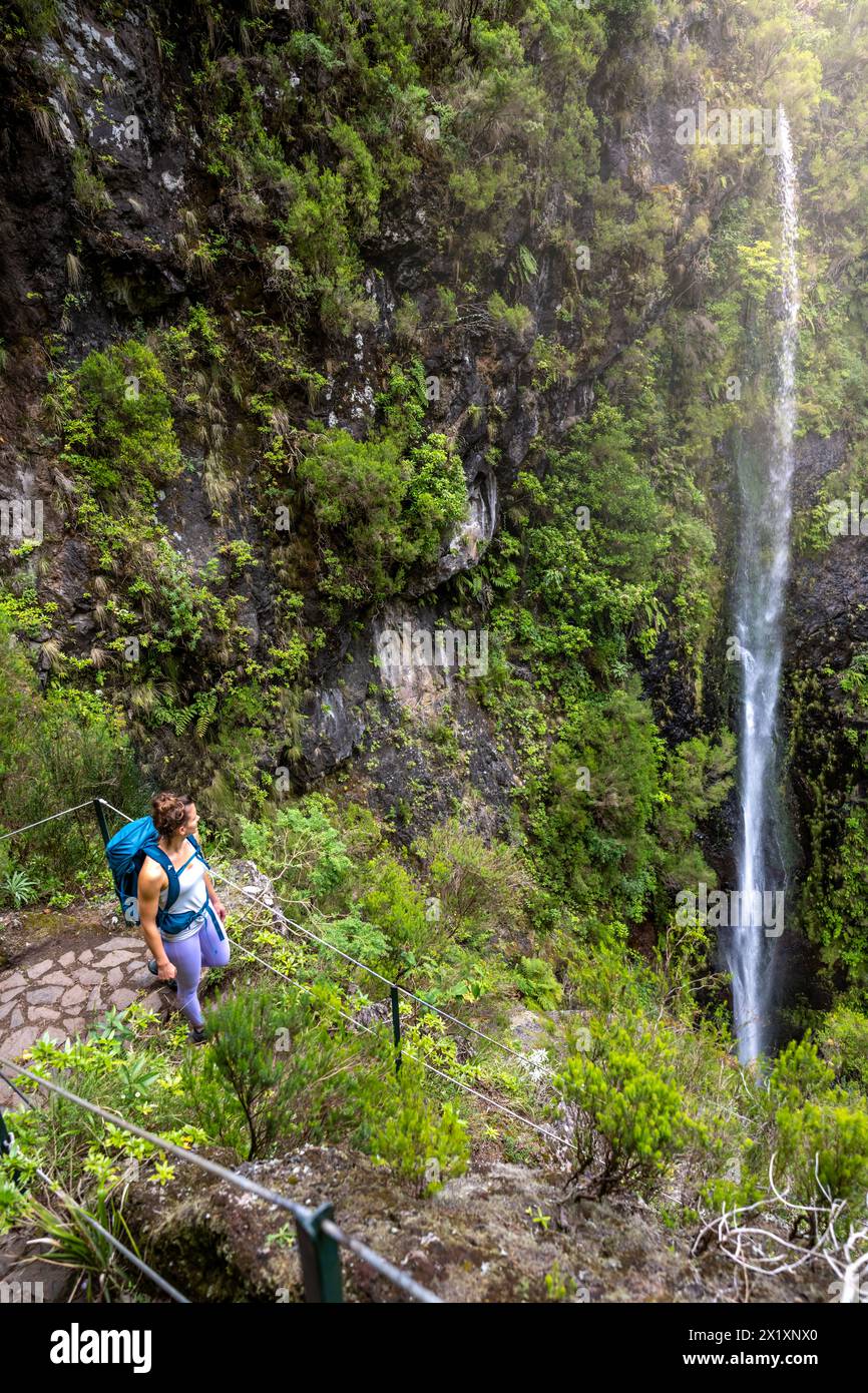 Description: Female backpacker tourist enjoys waterfall view from ...