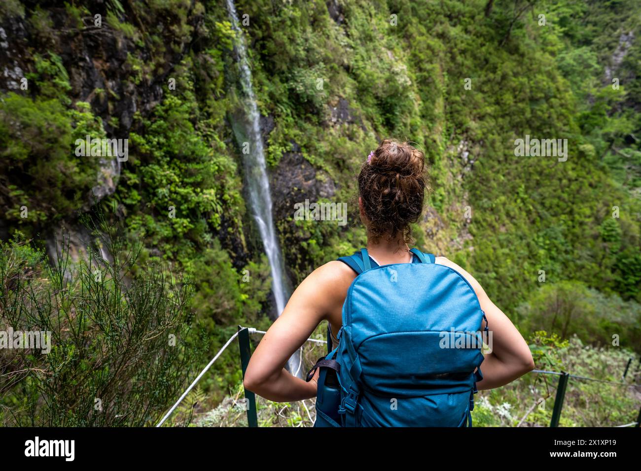 Description: Female backpacker tourist enjoys waterfall view from ...