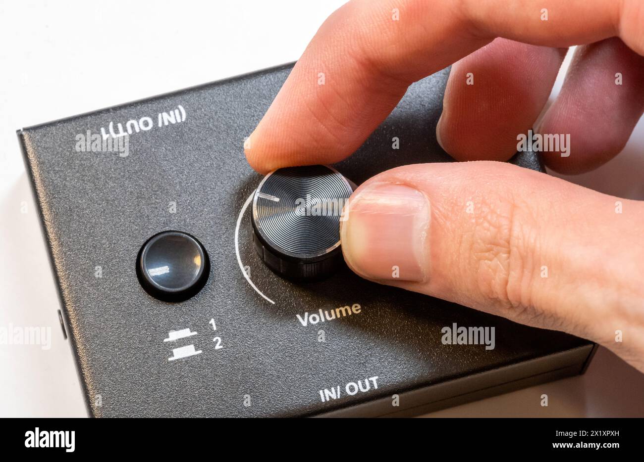 Close-up view of a mans hand turning up adjusting the volume knob on a modern audio device ...
