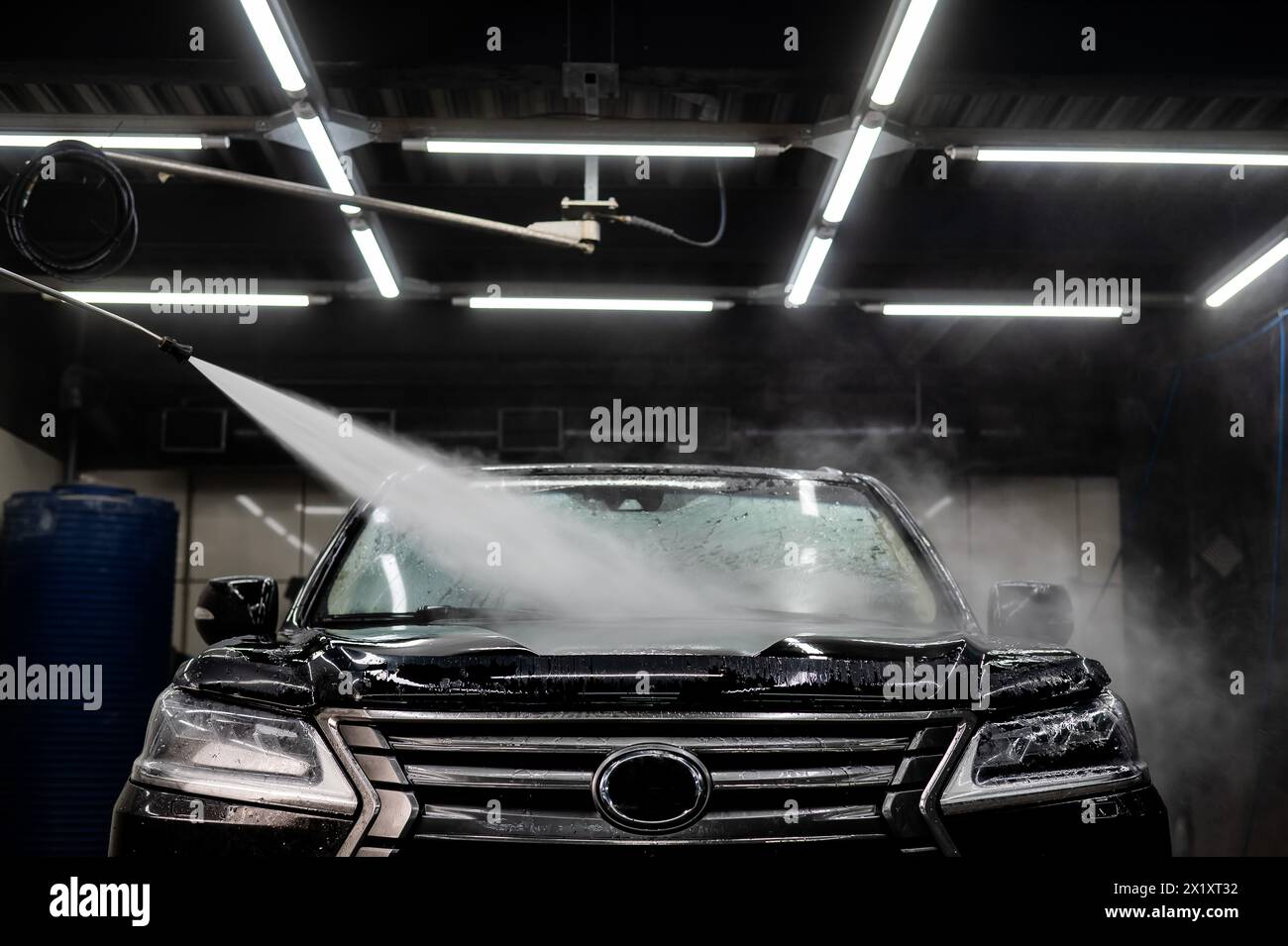 A man washes foam off a black car with water at a car wash Stock Photo ...