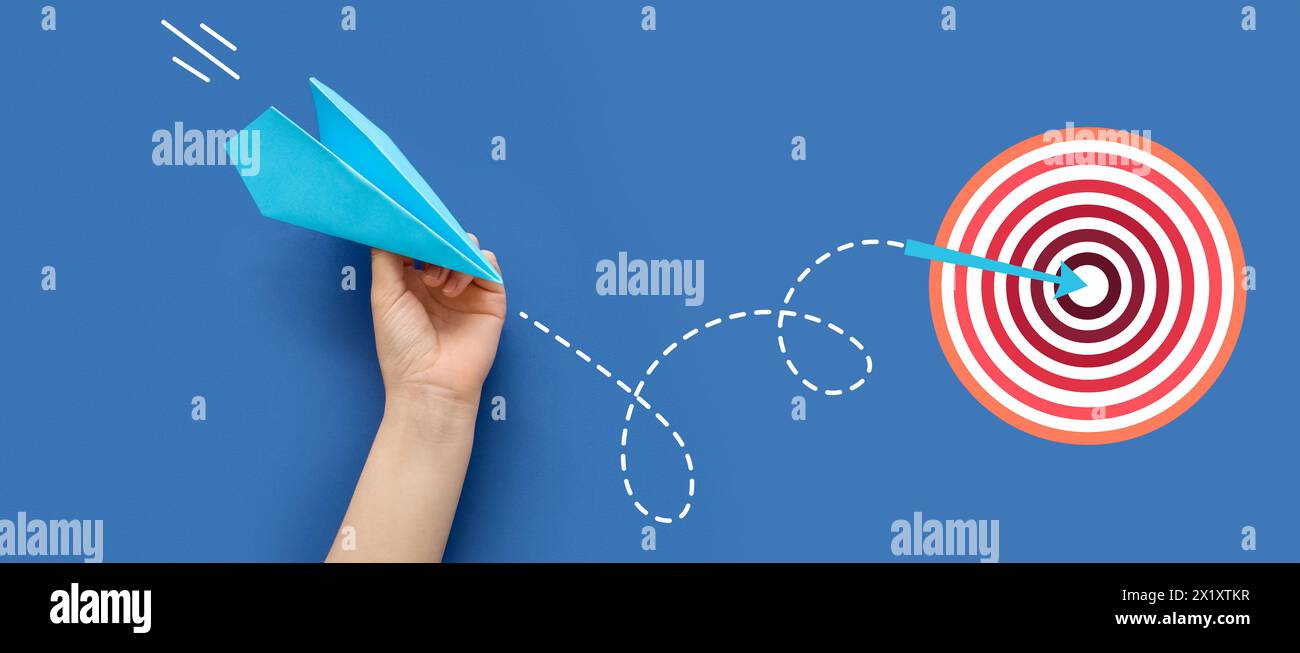 Hand with paper plane and drawn dartboard on blue background. Concept ...