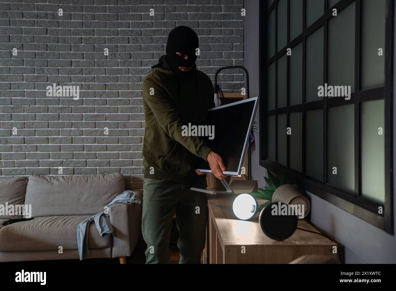 Male thief stealing computer monitor in room at night Stock Photo - Alamy