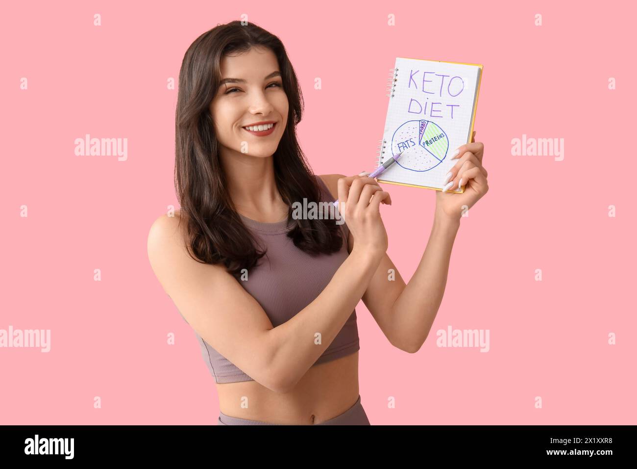 Happy smiling young woman pointing at notebook with keto diet chart on ...