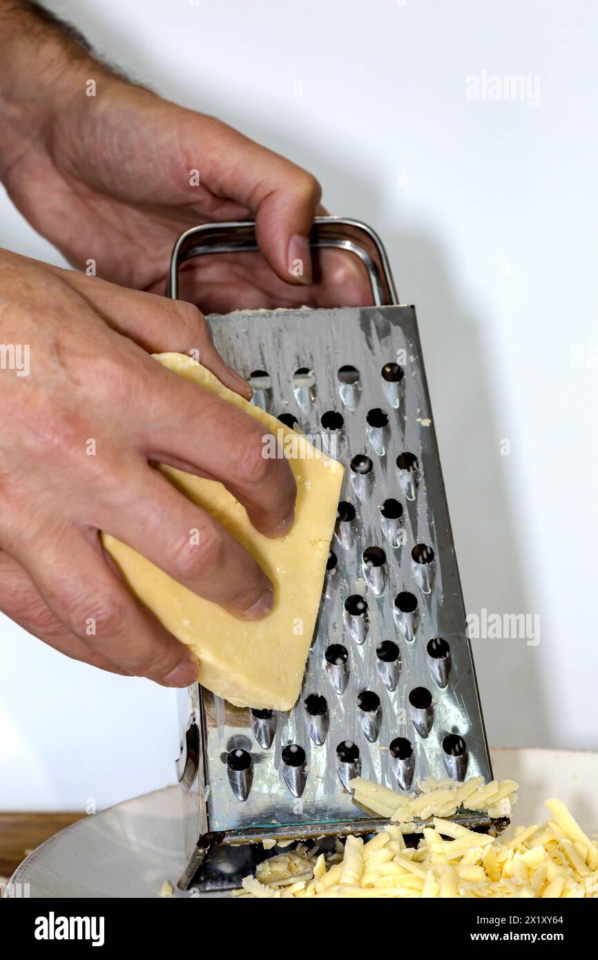 A mans hands holding a block of cheese and grating it Stock Photo - Alamy