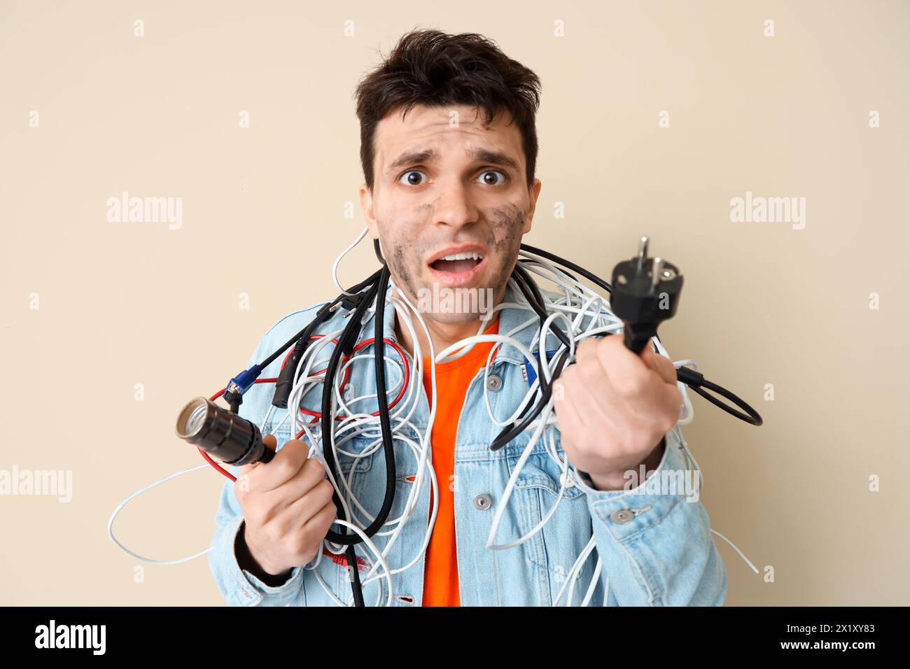 Electrocuted young man with burnt face and wires on beige background ...