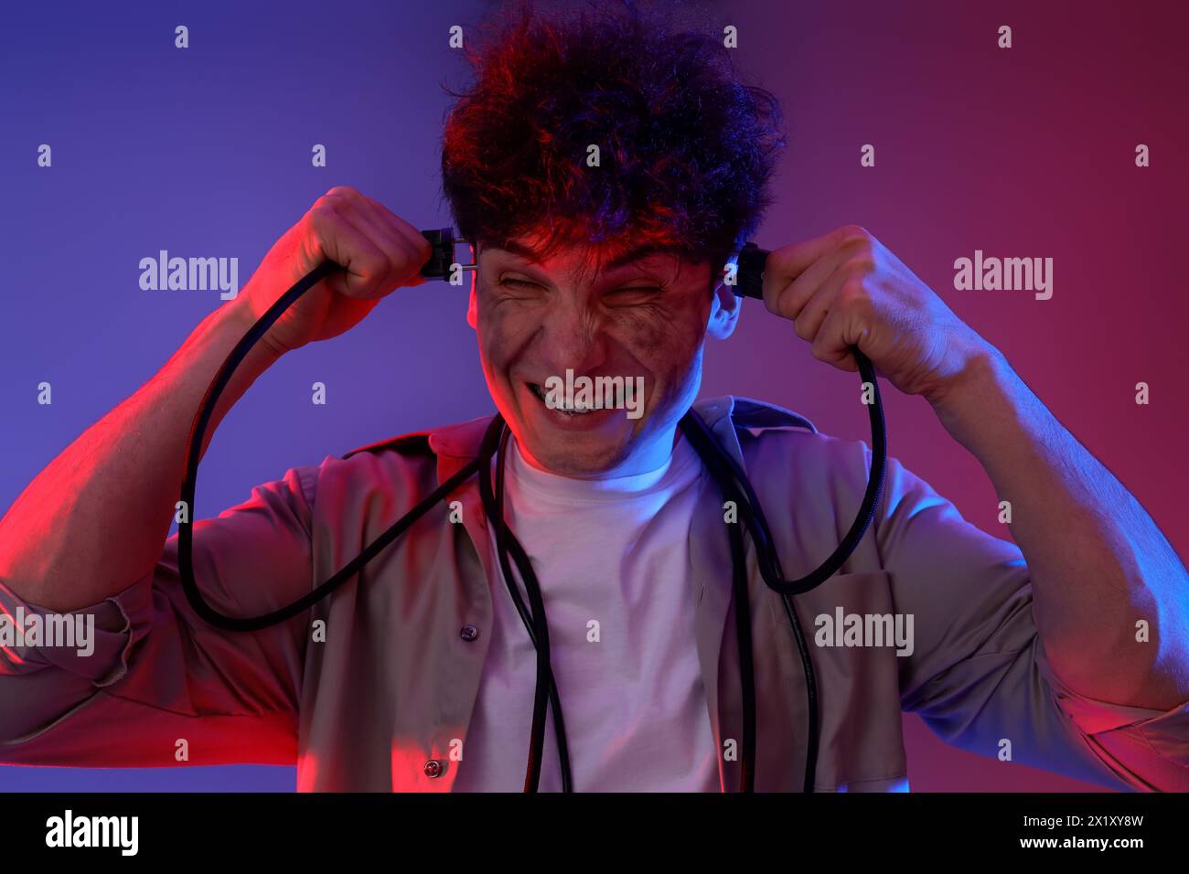 Electrocuted young man with burnt face and plugs on dark background ...
