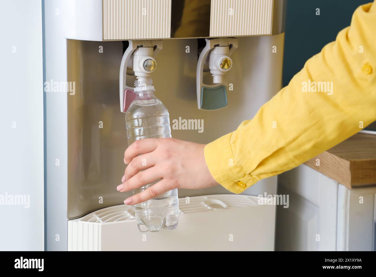 Female hand filling plastic bottle with filtered water from cooler near ...