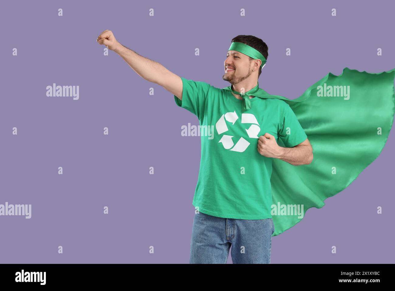 Young man dressed as eco superhero on lilac background. Ecology concept ...