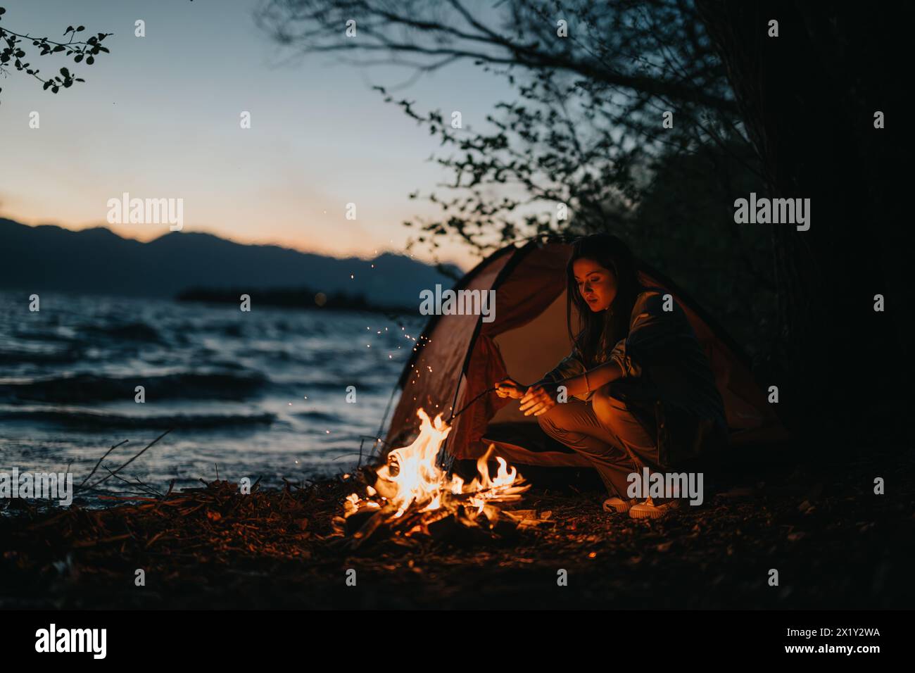 Friends enjoying togetherness at a lakeside campfire on a camping trip ...