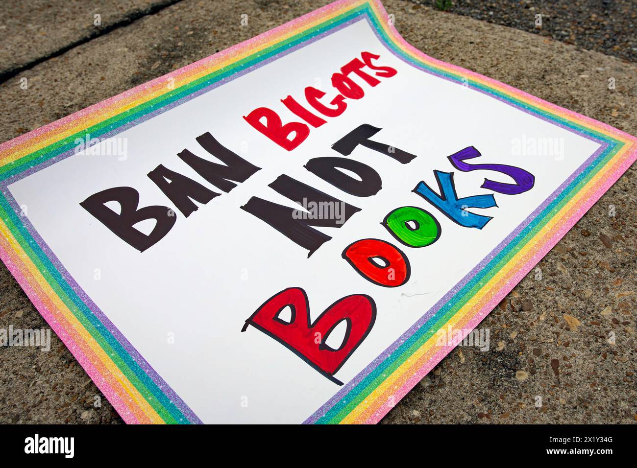A hand- drawn protest sign lying on the sidewalk that reads, Ban Bigots ...