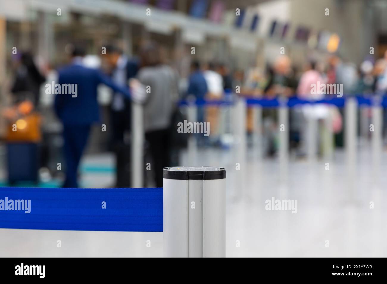 A metallic barrier pole with a blue retractable belt with waiting ...
