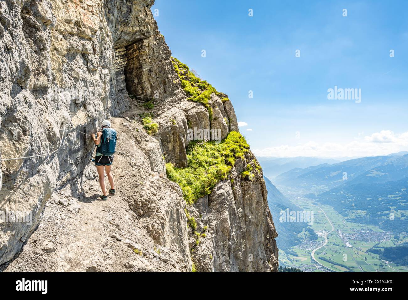 Description: Sporty woman hikes along steep rocky hike trail with ...