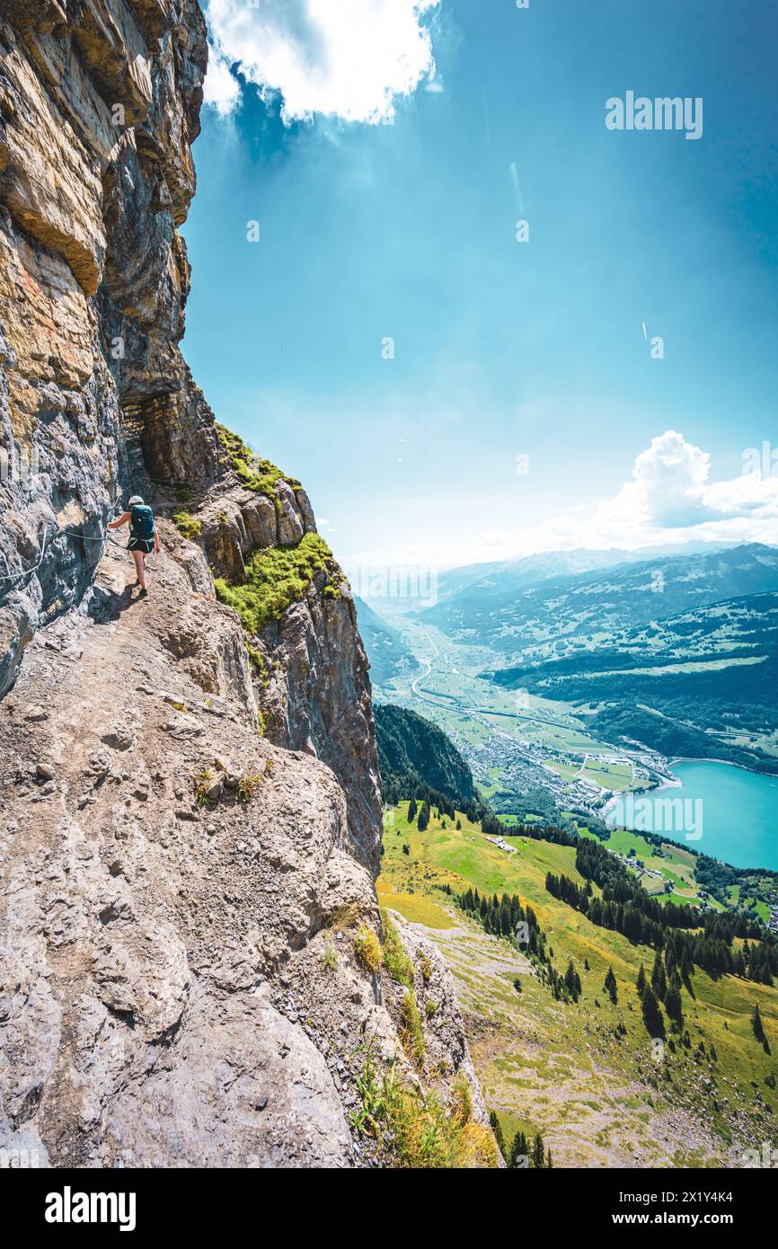 Description: Sporty woman hikes along steep rocky hike trail with ...