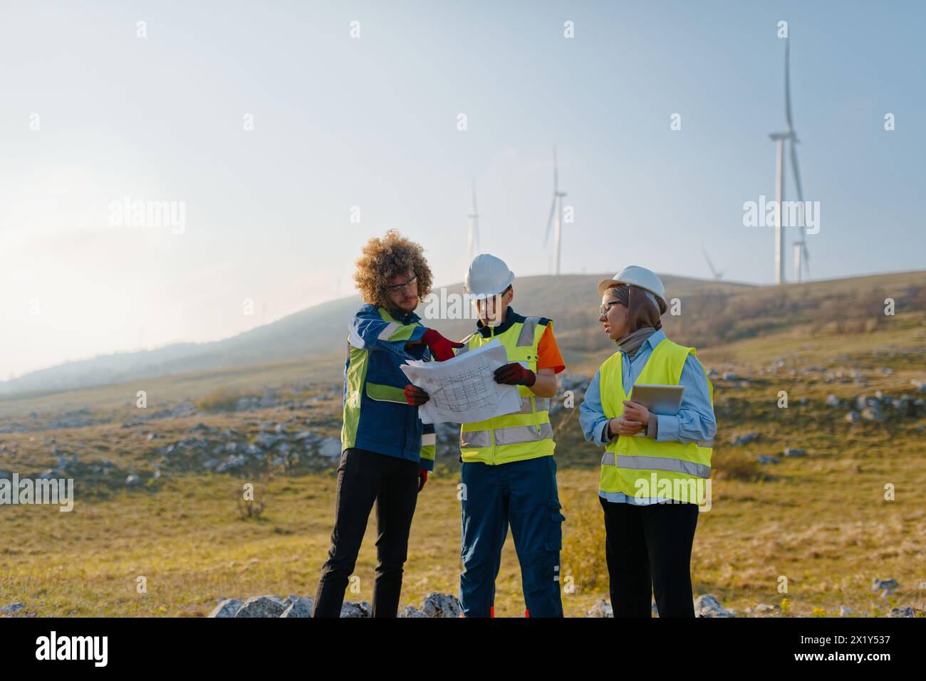 A team of engineers and workers oversees a wind turbine project at a ...