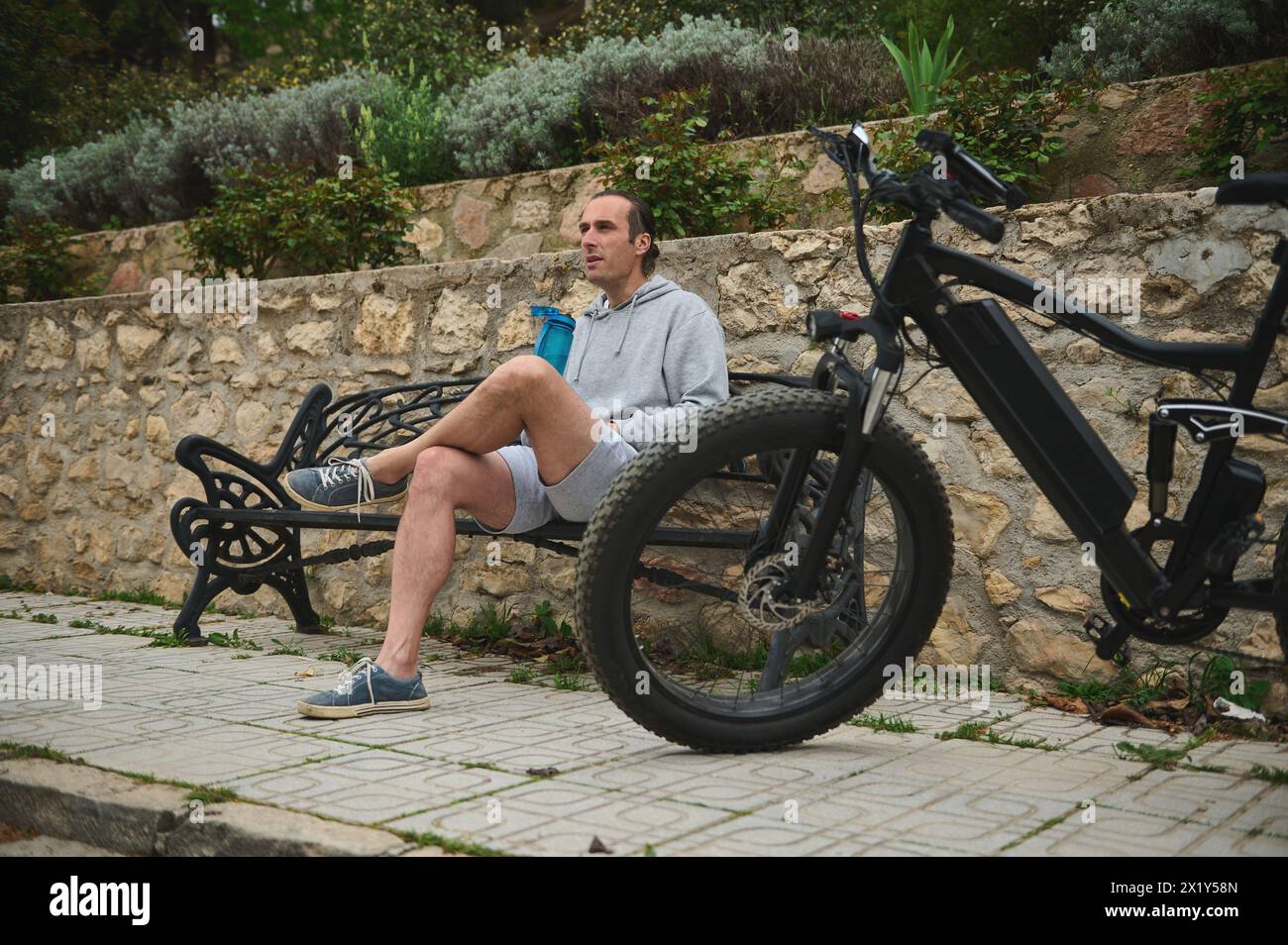 Handsome young cyclist man in sportswear, drinking water from sports ...