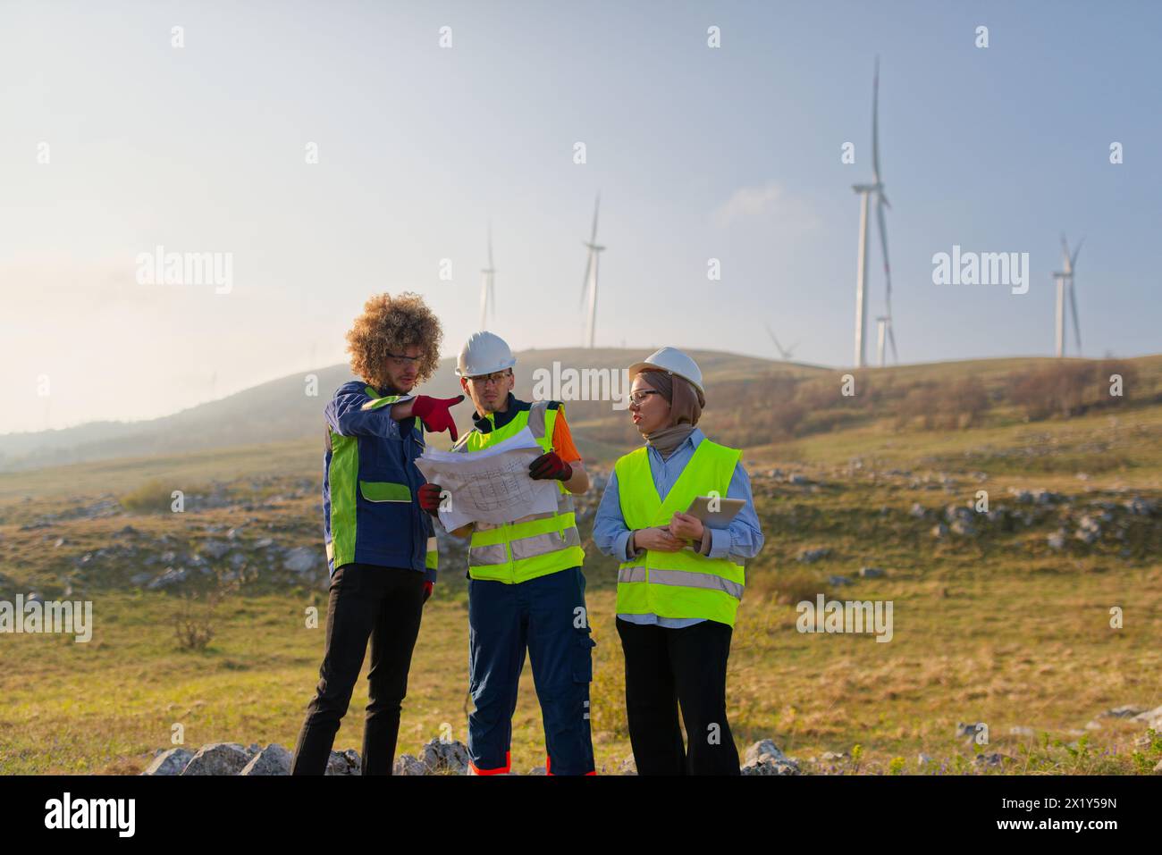 A team of engineers and workers oversees a wind turbine project at a ...