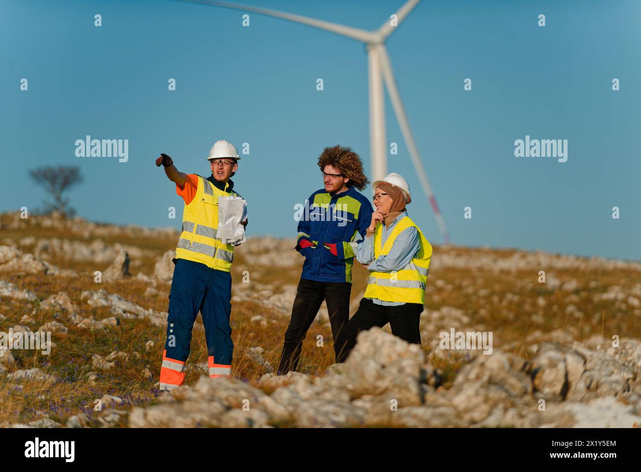 A team of engineers and workers oversees a wind turbine project at a ...
