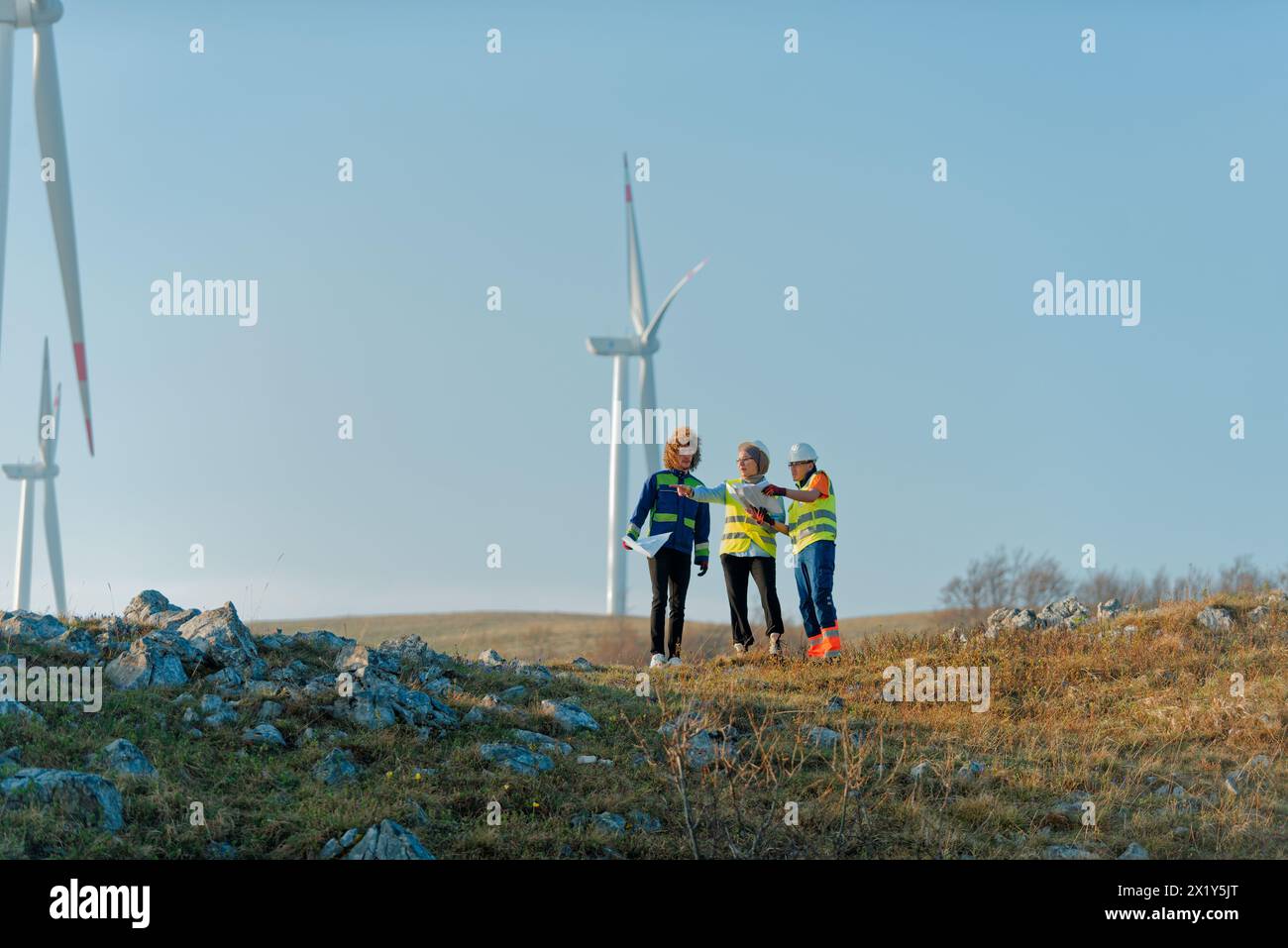 A team of engineers and workers oversees a wind turbine project at a ...