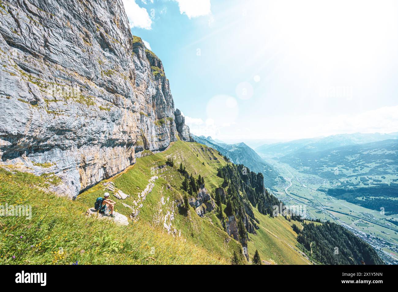 Description: Mountaineer sits on a rock next to the hiking trail and ...