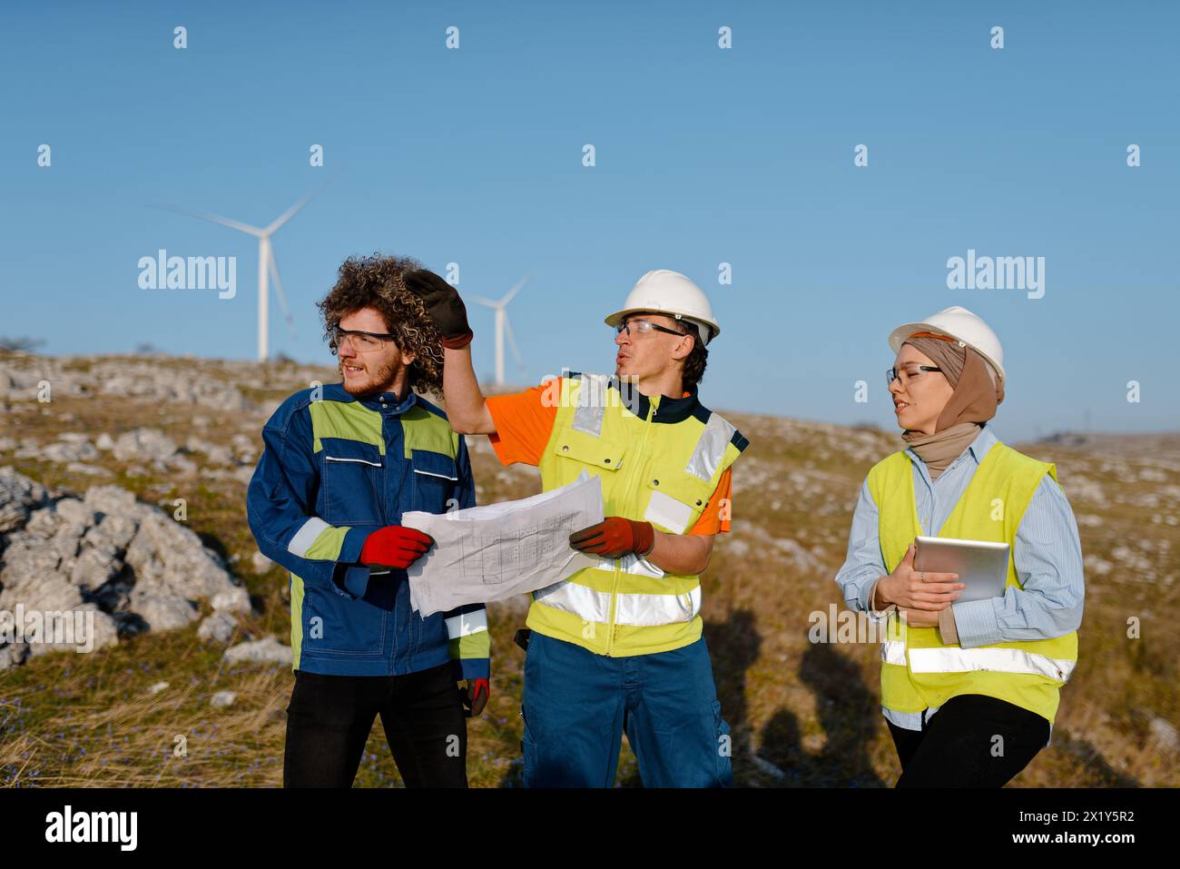 A team of engineers and workers oversees a wind turbine project at a ...