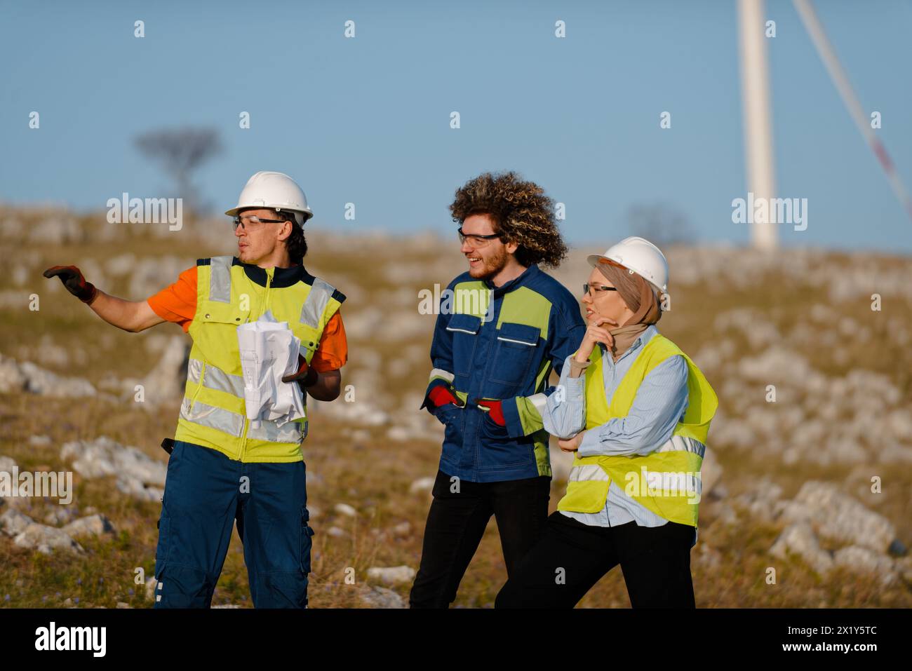 A team of engineers and workers oversees a wind turbine project at a ...