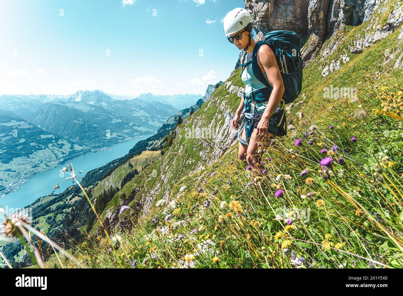 Description: Side view of sportive woman hiking on flowery trail next ...