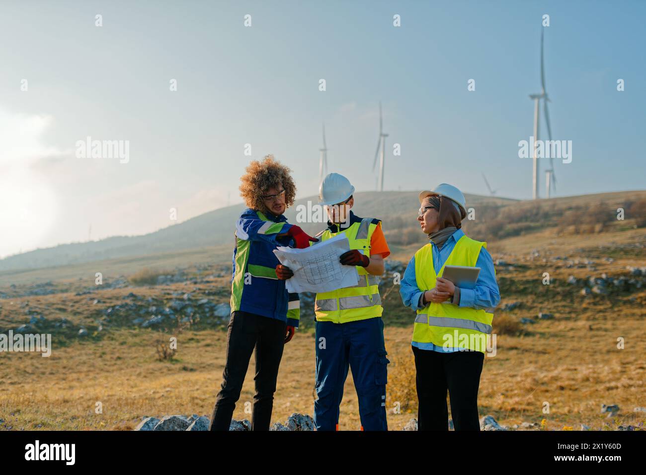 A team of engineers and workers oversees a wind turbine project at a ...