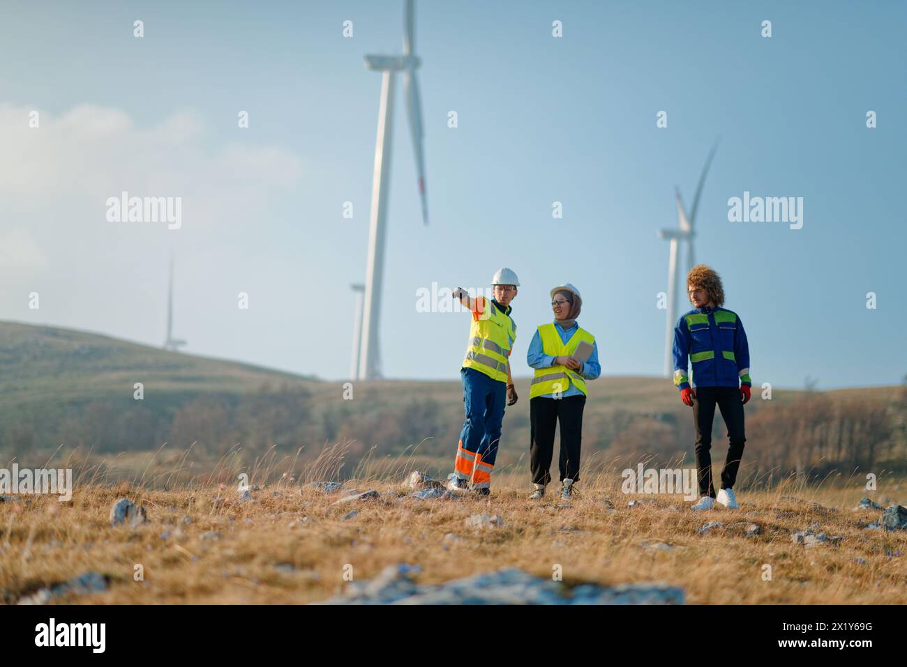 A team of engineers and workers oversees a wind turbine project at a ...