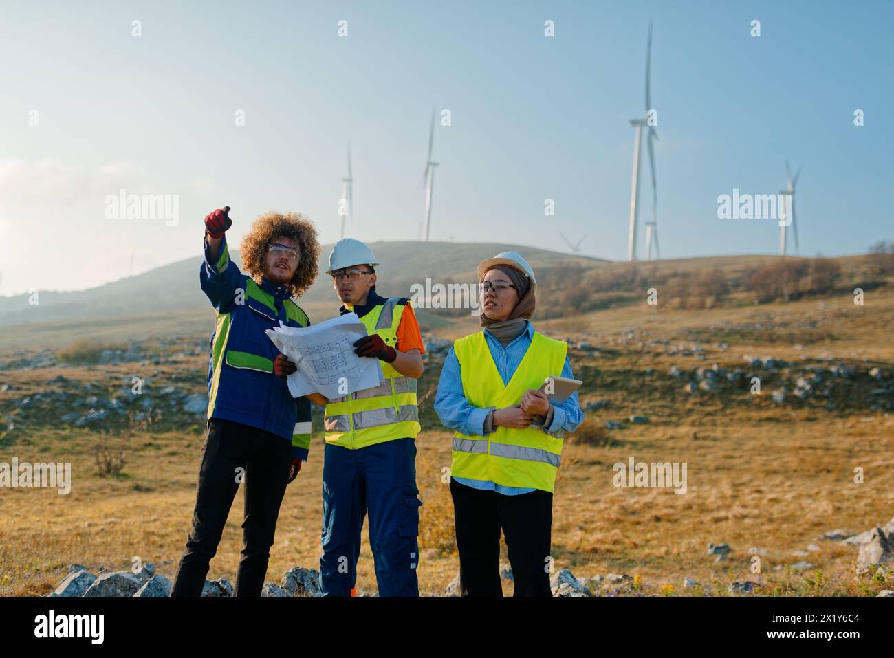 A team of engineers and workers oversees a wind turbine project at a ...