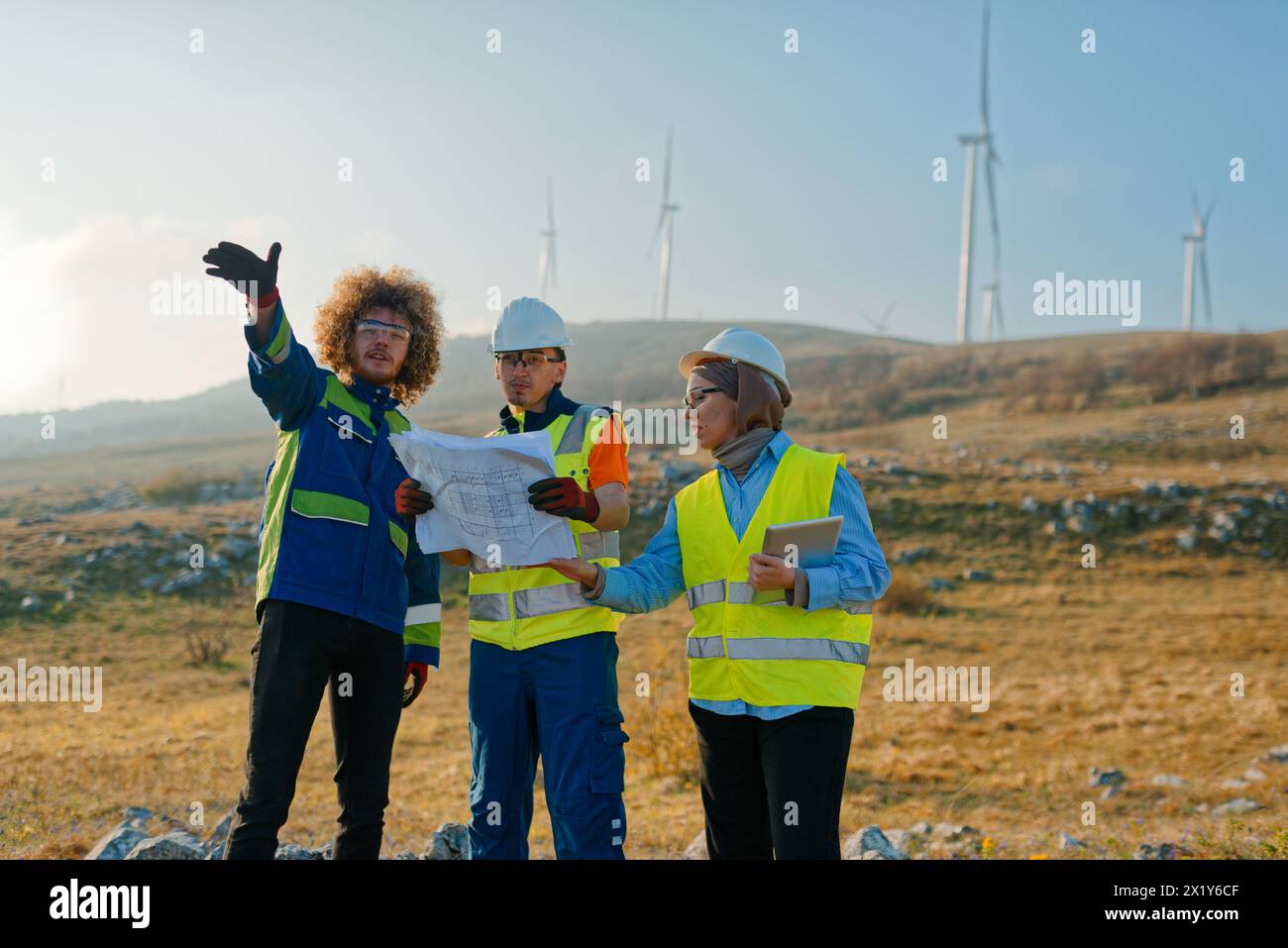 A team of engineers and workers oversees a wind turbine project at a ...
