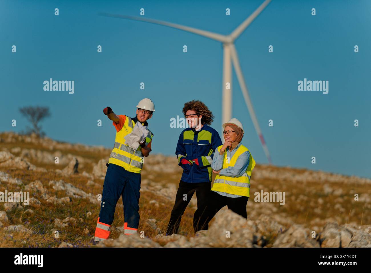A team of engineers and workers oversees a wind turbine project at a ...