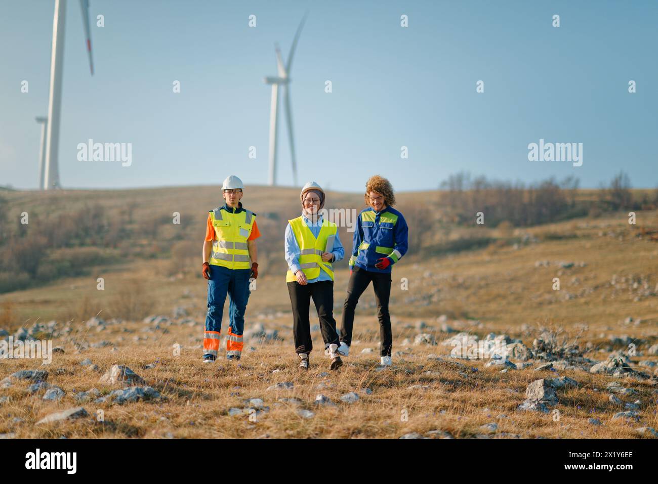 A team of engineers and workers oversees a wind turbine project at a ...