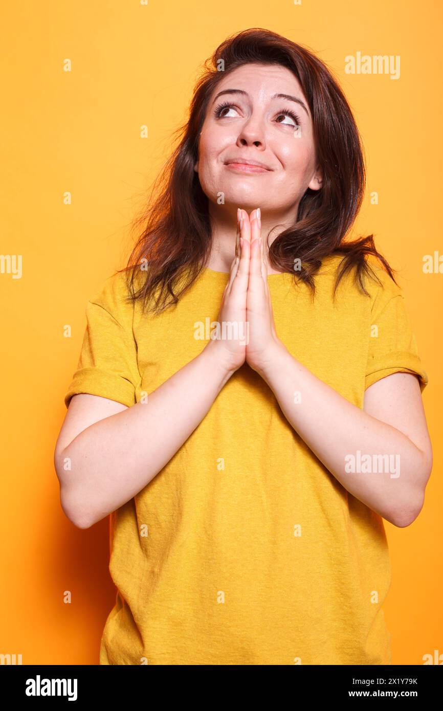 Casual caucasian lady hopelessly looking up and praying with palms ...