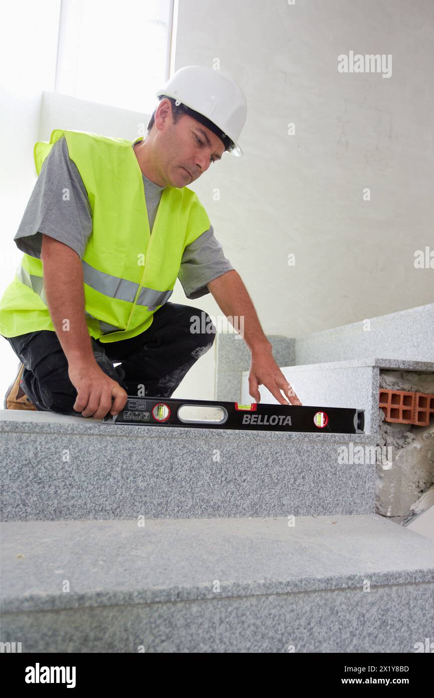 Worker with protective equipment, PPE, Leveling ladder rung, housing ...