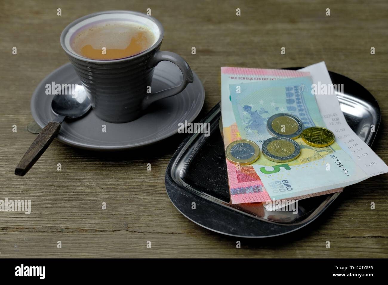 small gray cup of coffee on a wooden table, metal tray for money, euro ...