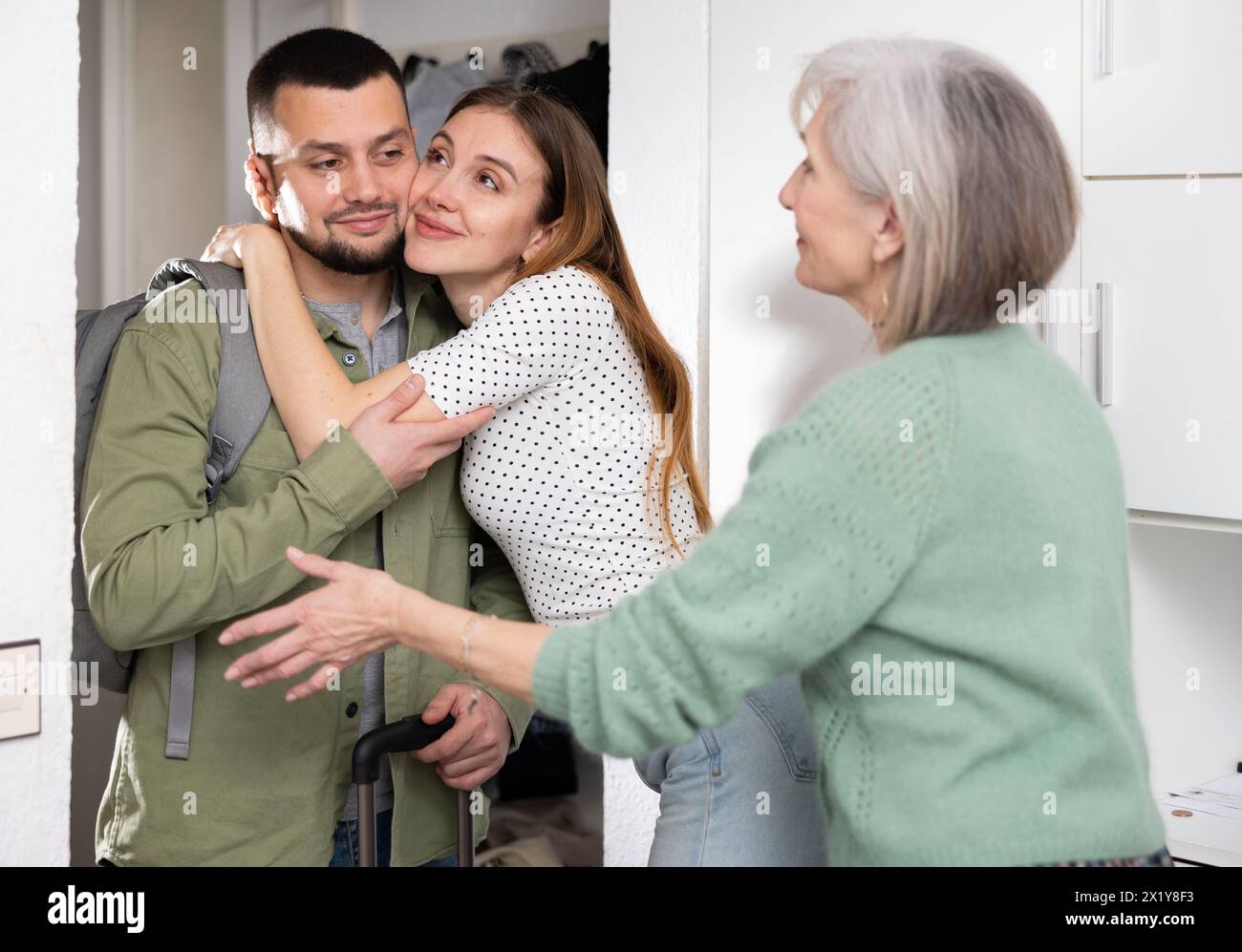 Woman and her mother welcoming man at home Stock Photo - Alamy