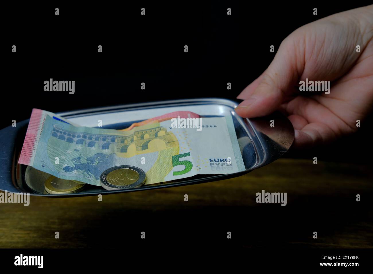 close-up of a metal tray for money in a female hand, euro banknotes and ...