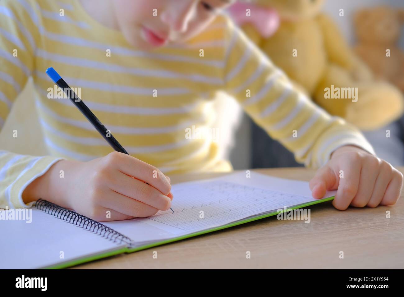 child, schoolboy in yellow t-shirt, writes letters in notebook with an ...