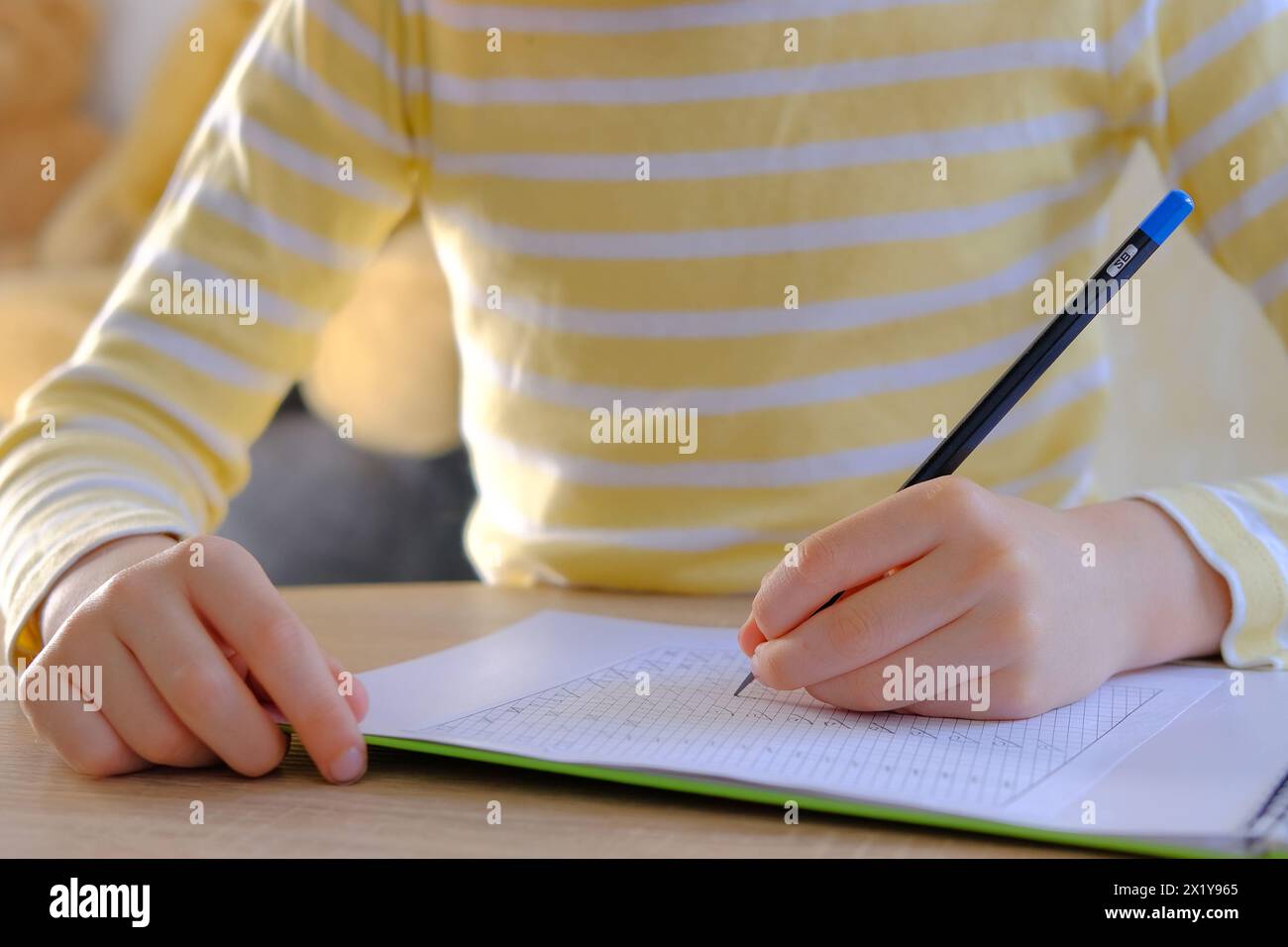 child, schoolboy in yellow t-shirt, writes letters in notebook with an ...