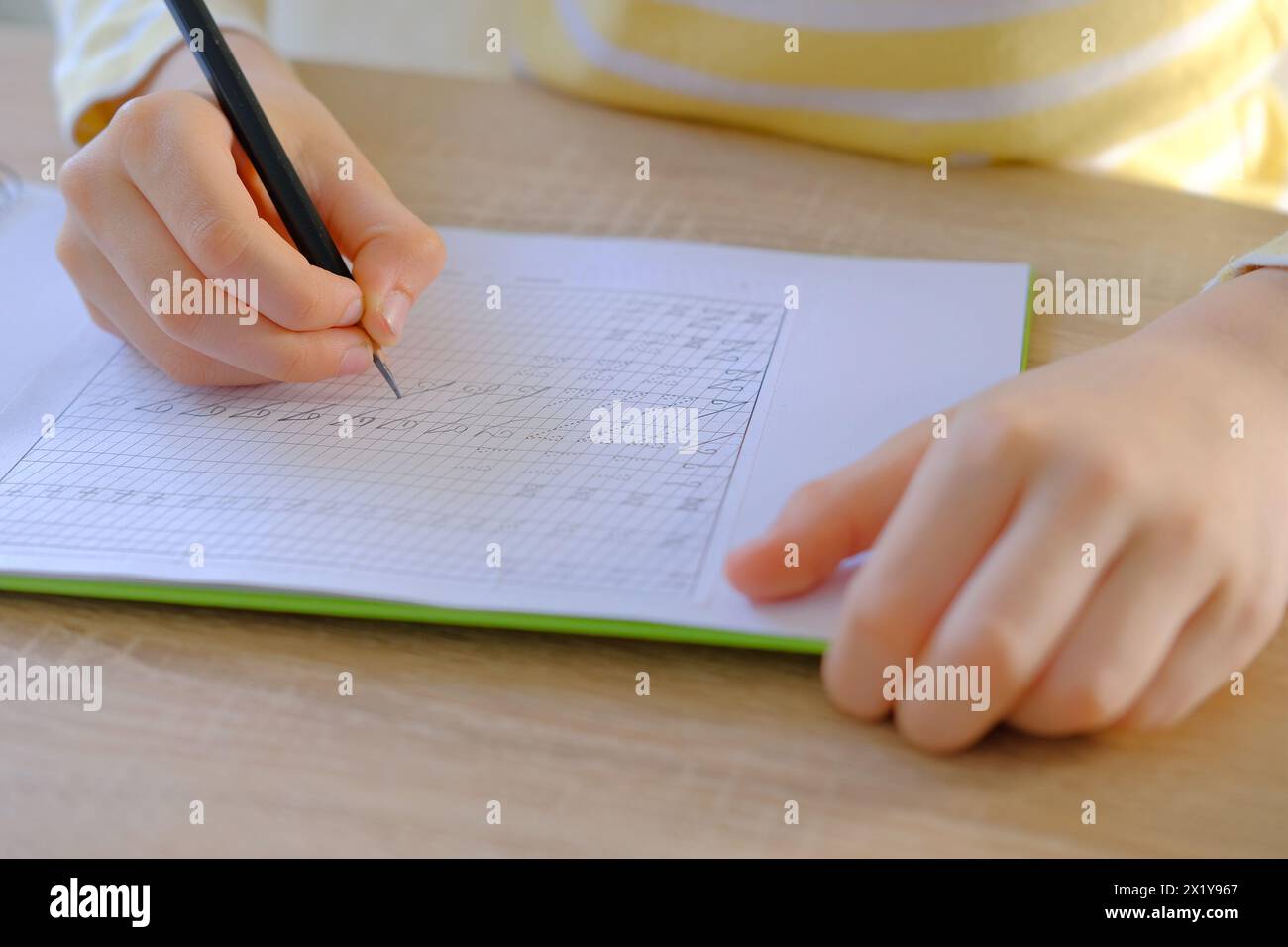child, schoolboy in yellow t-shirt, writes letters in notebook with an ...