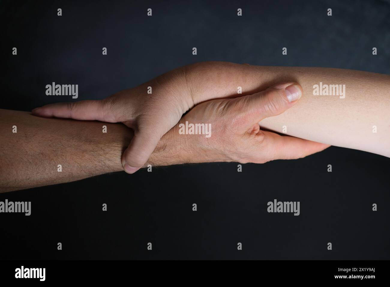 male and female hands together on black background, old skin with ...