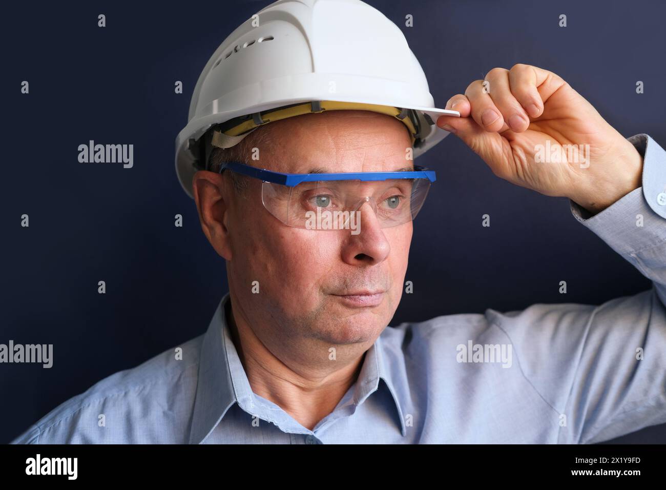 elderly male engineer, builder in protective helmet, glasses looking ...