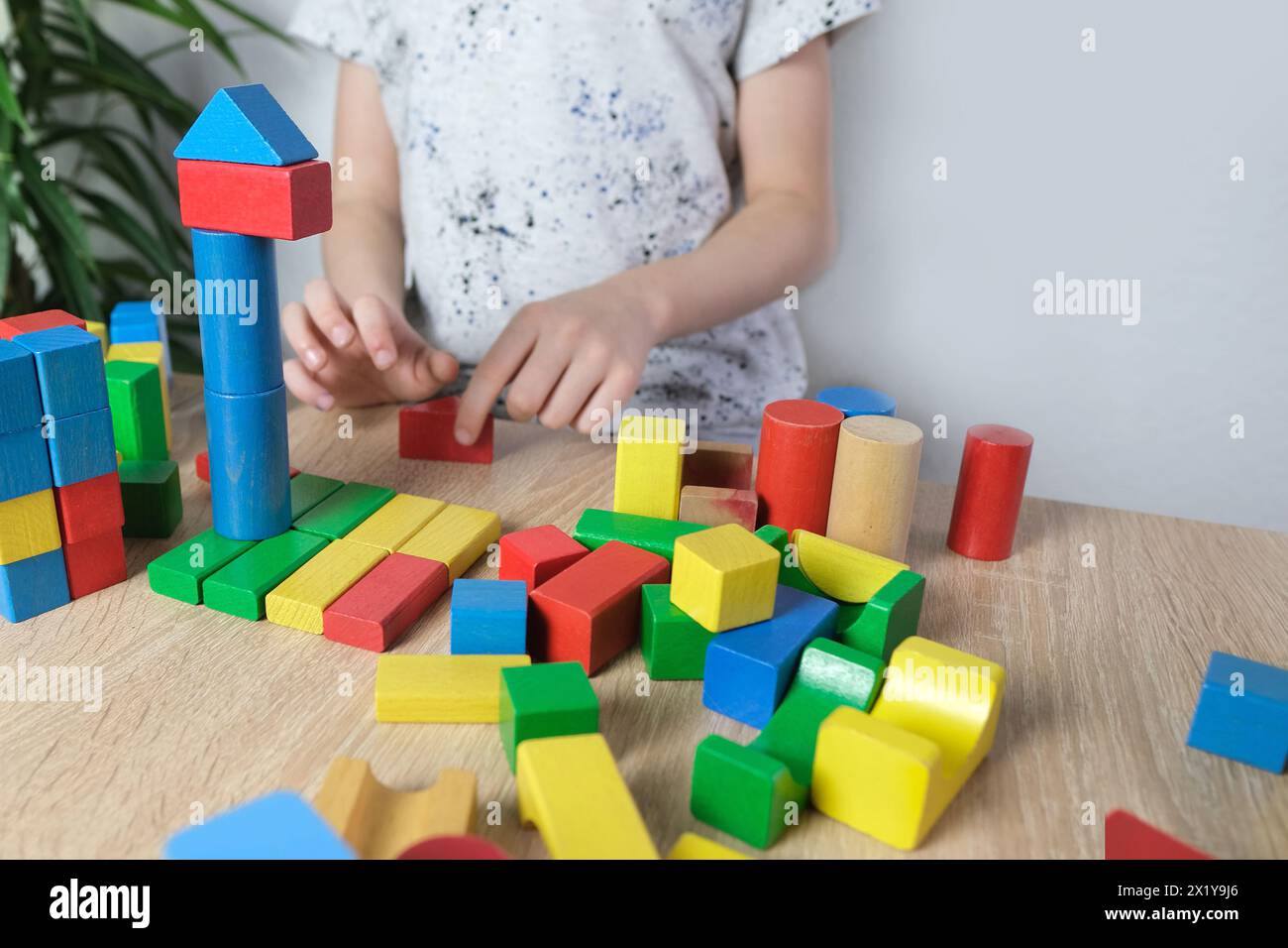 small child, kid plays with colored wooden cubes, builds houses and ...