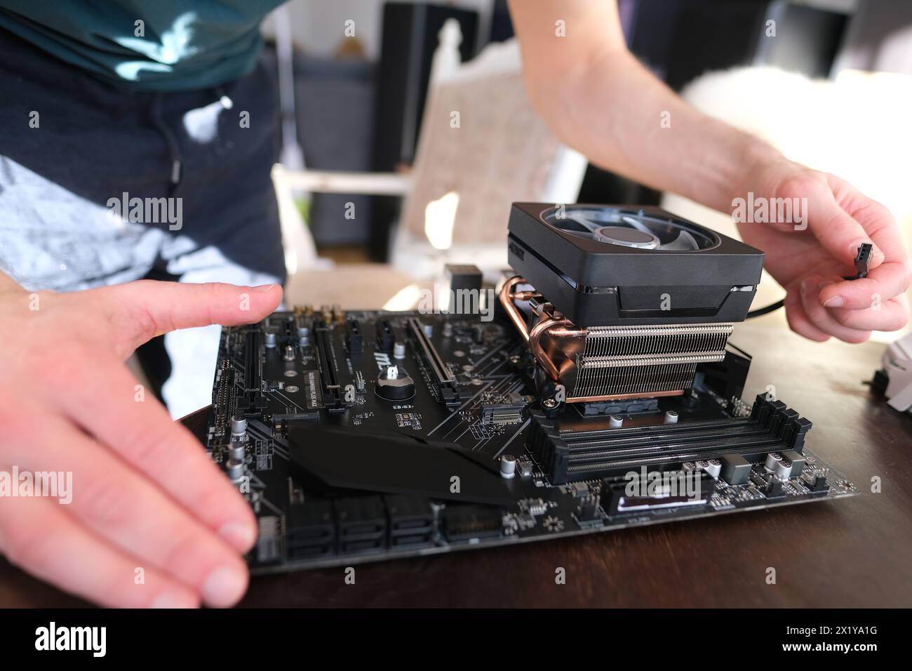 hands of young male master install cooler with copper heat pipes for the processor, other parts ...