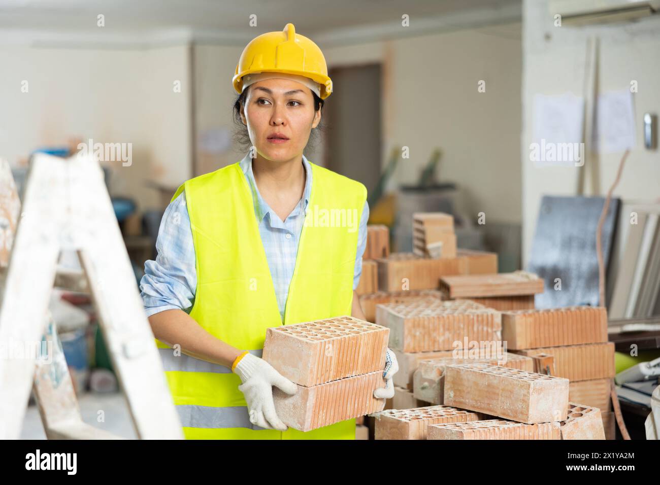 Female builder carrying bricks at renovating object Stock Photo - Alamy