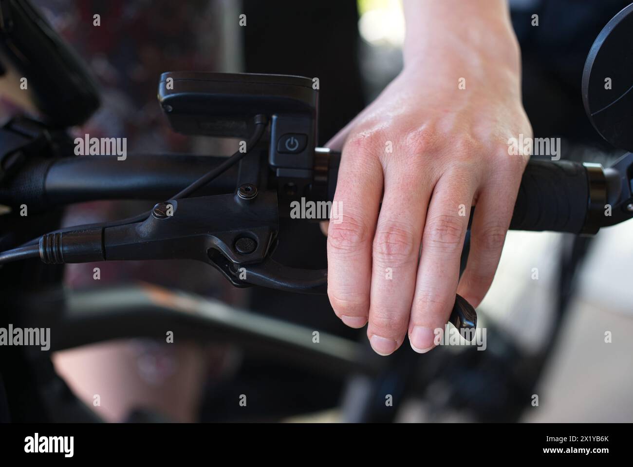 Close-up view of a female hand gripping a bicycle brake lever, with an ...